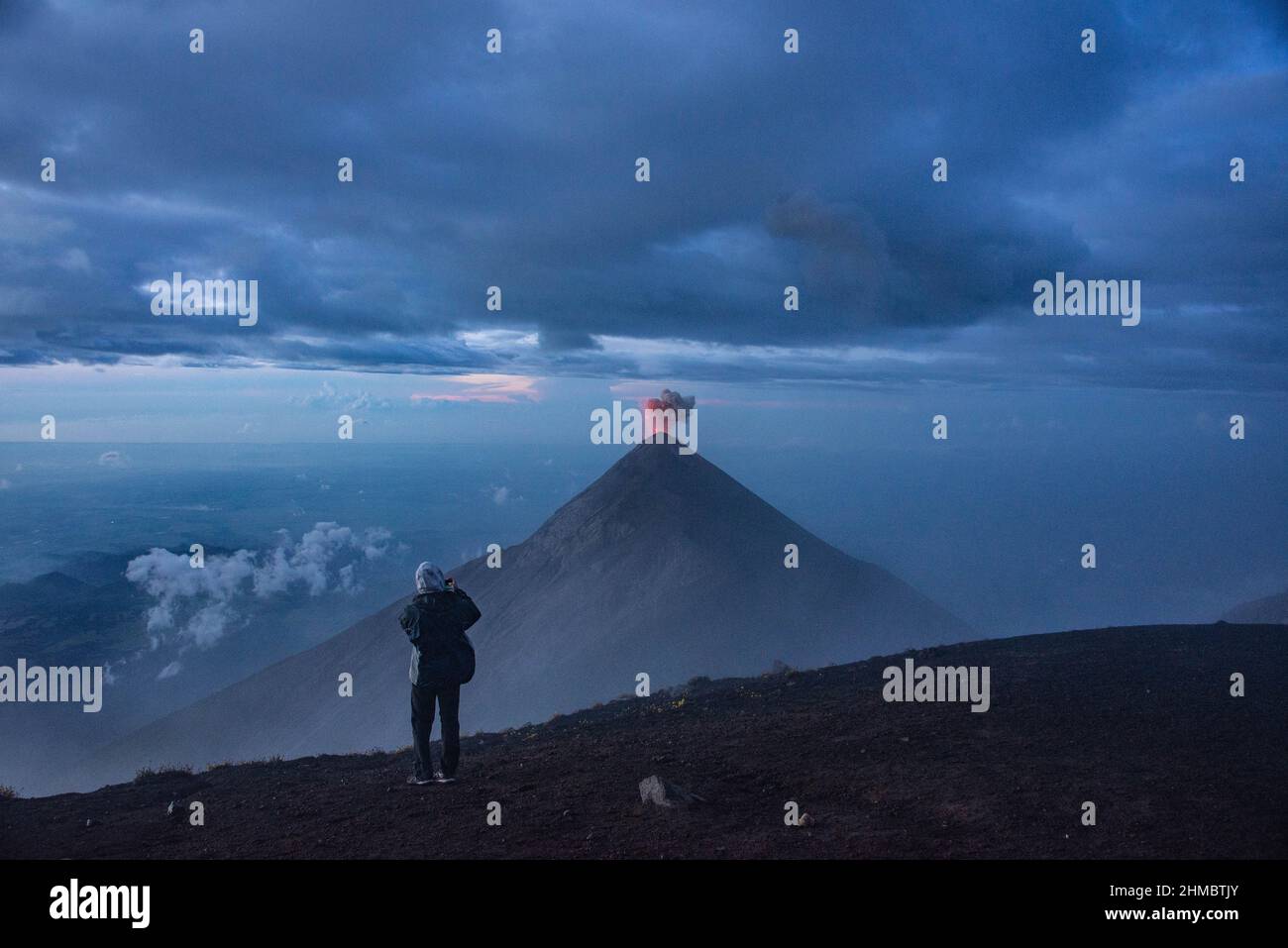 Climber on Acatenango watching Fuego volcano erupting, Antigua ...