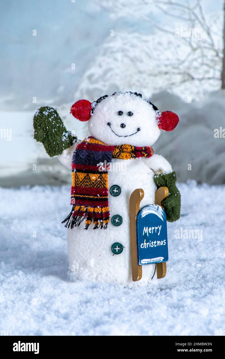 A happy snowman gives a jaunty wave as he stands with his sled in a ...