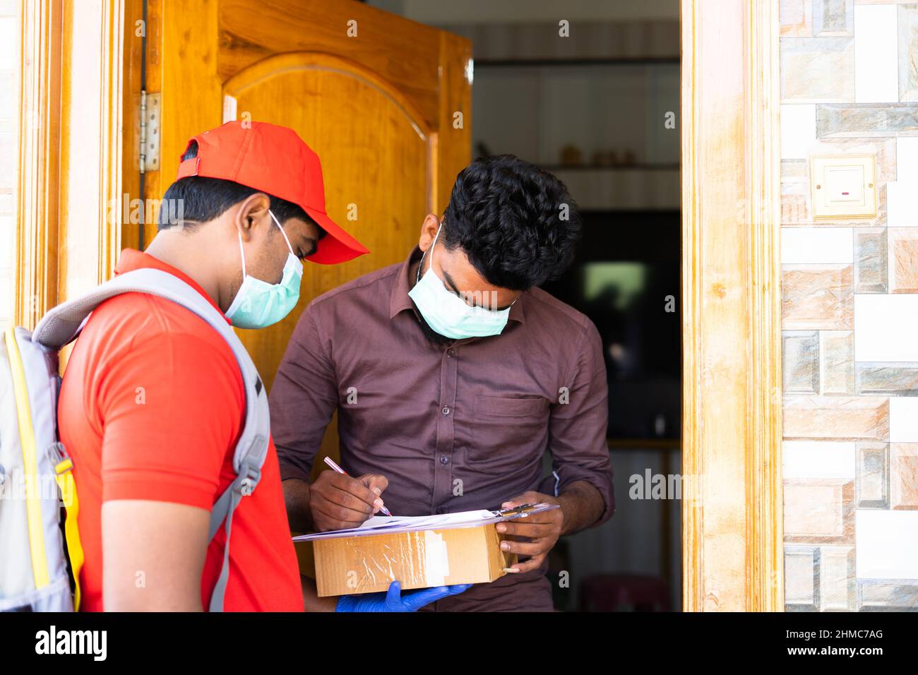 Focus on signing hands, Delivery boy with medical face mask giving ...