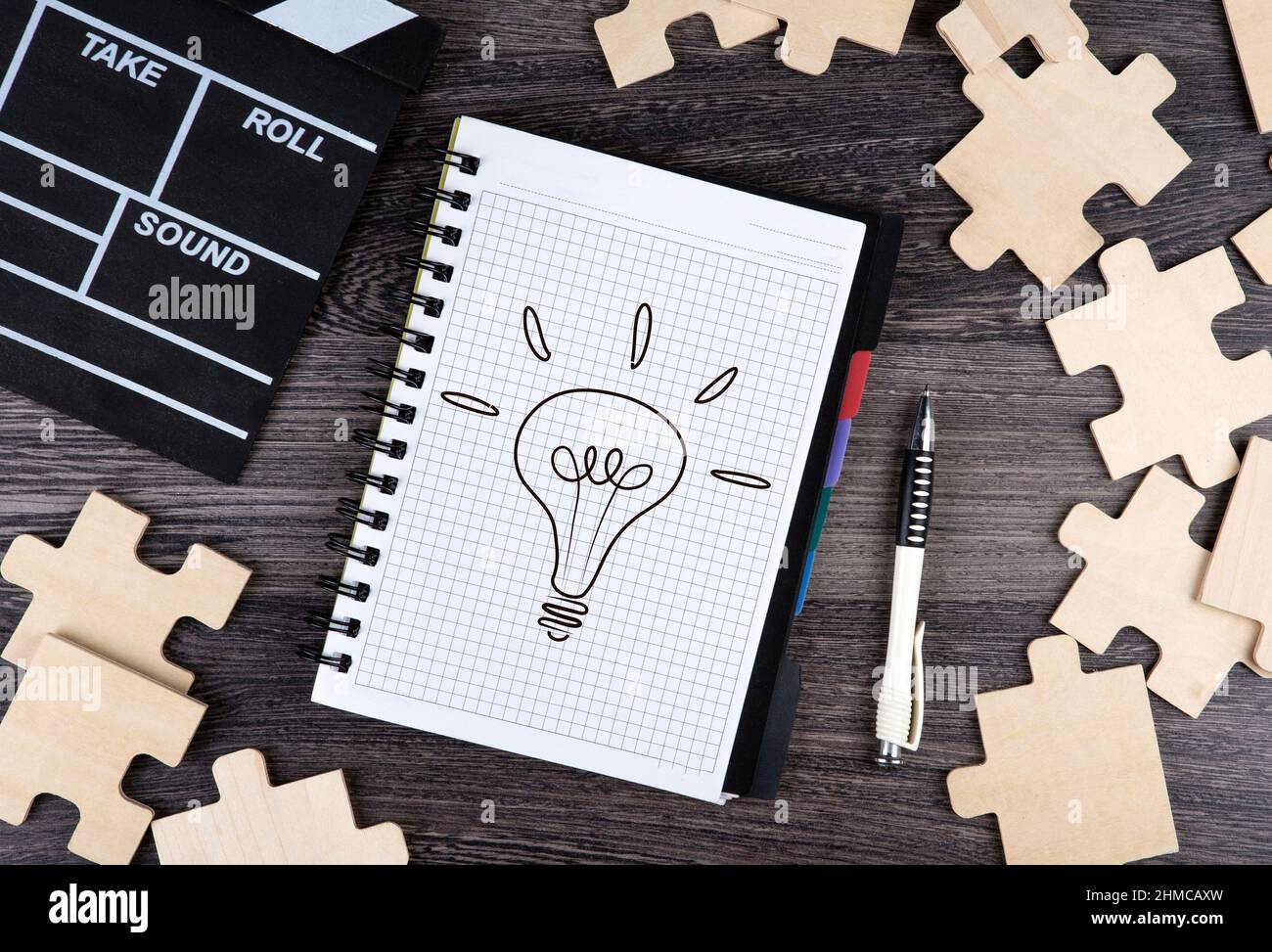 notepad with cinematic clapper, pen and puzzle pieces on a table top ...