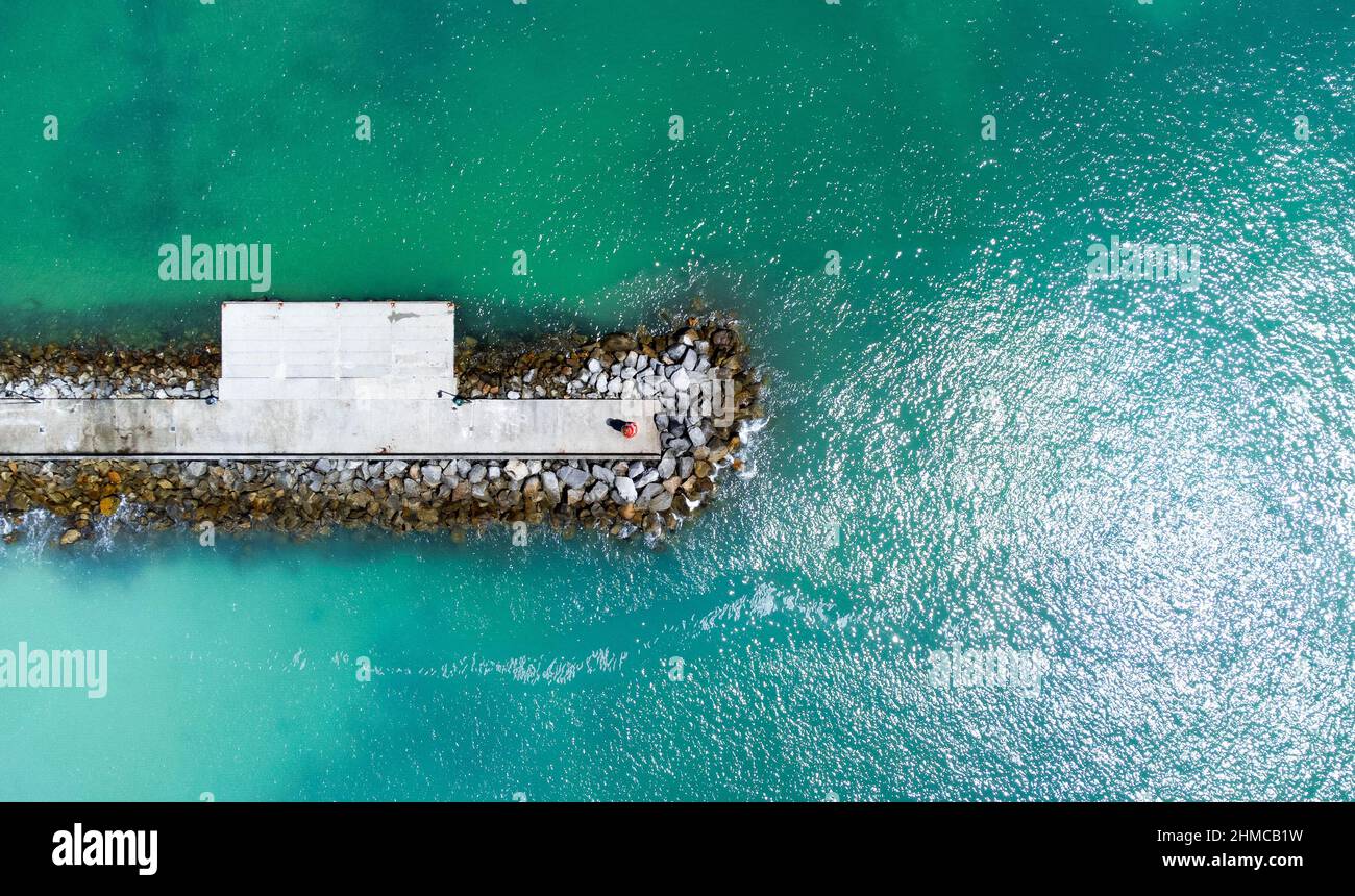 ocean pier in beautiful blue water with small lighthouse on the end of ...