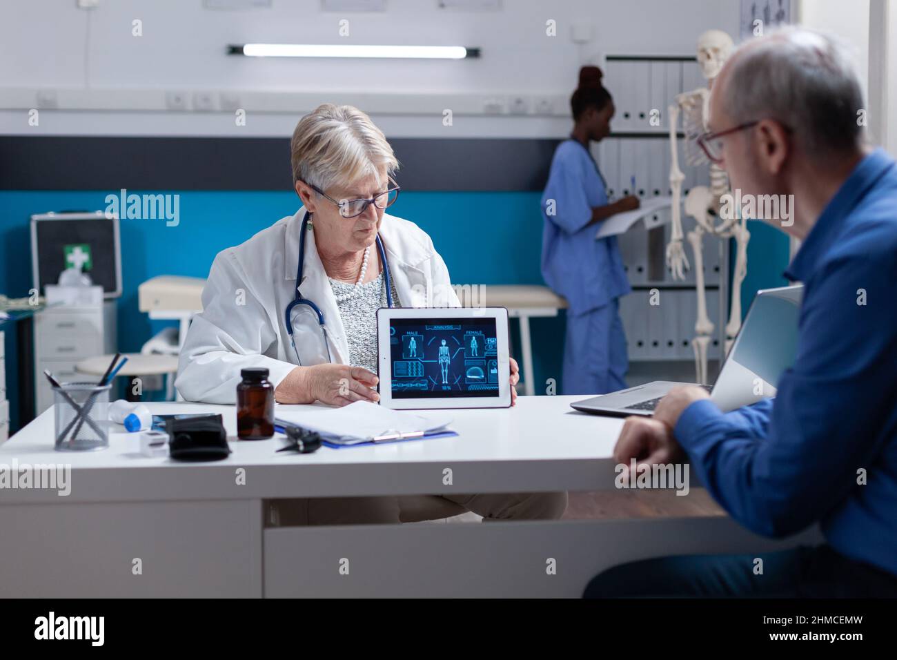 Medic showing tablet with illustration of human body analysis to senior ...