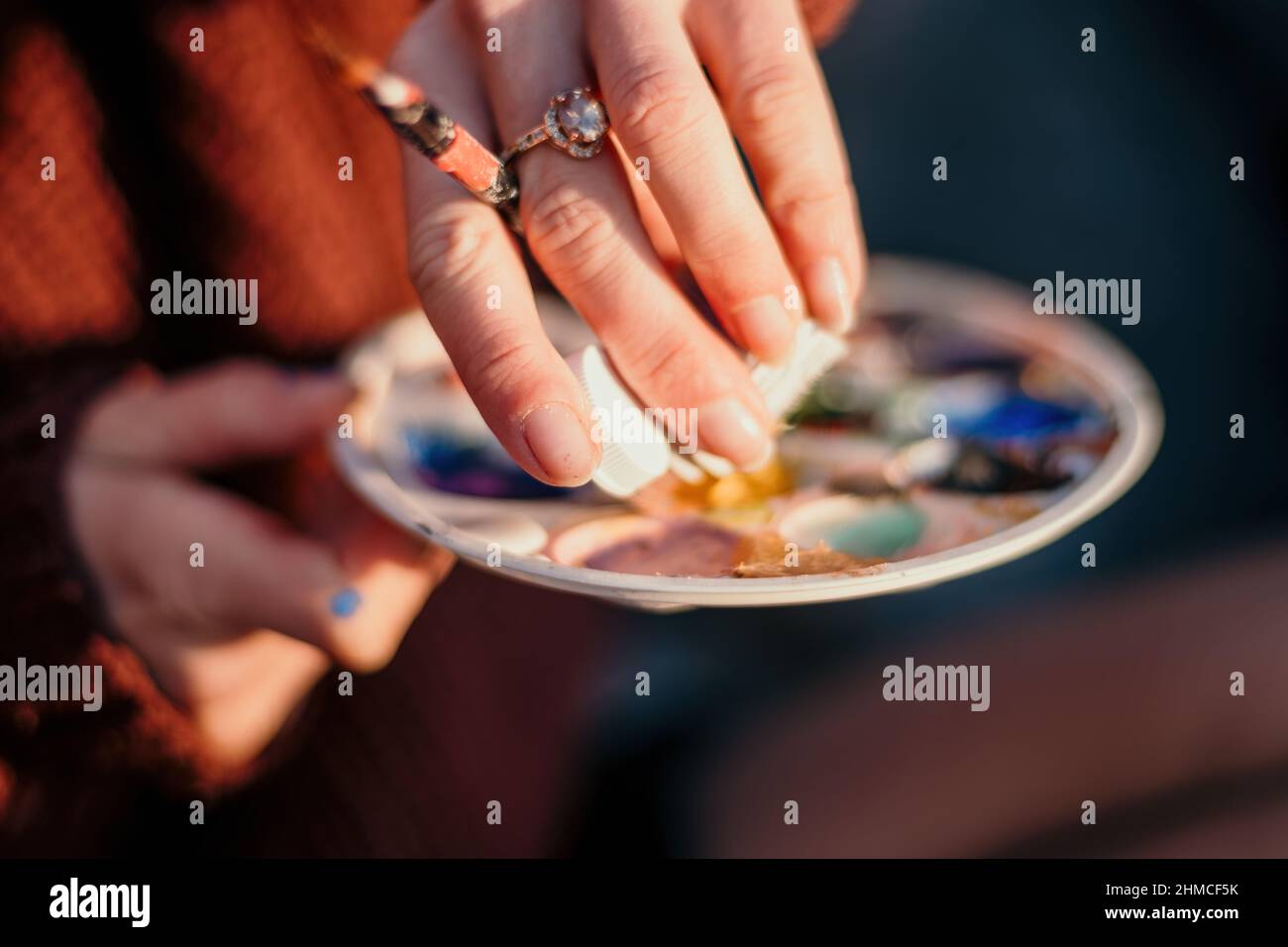 A woman's hands mixing paints on a palette board. Preparing to paint a ...