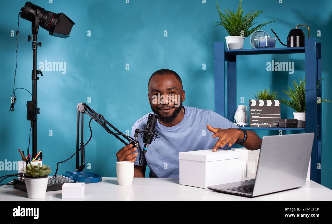 Vlogger holding boom arm microphone presenting giveaway product box in ...