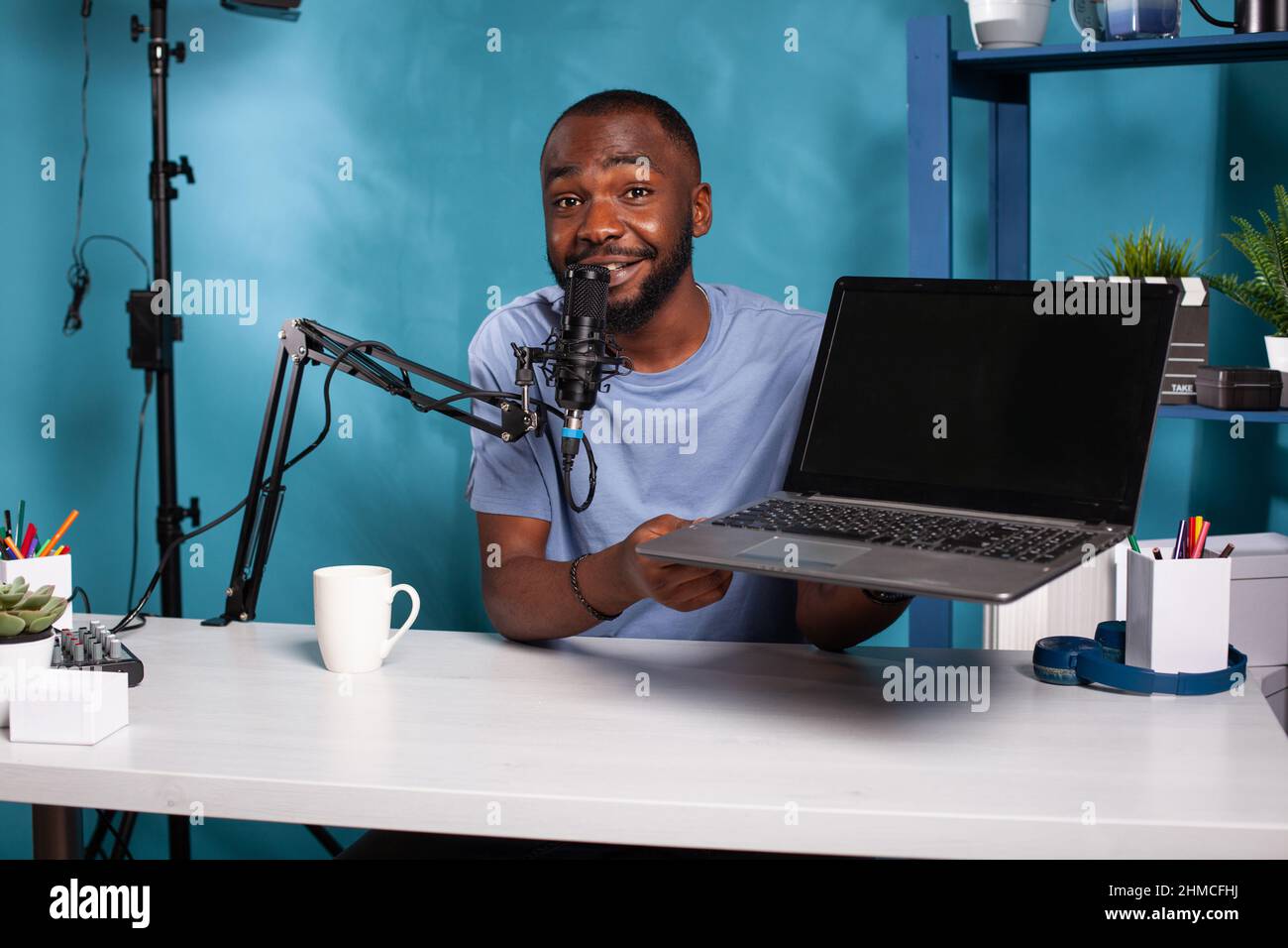 Smiling digital technology reviewer holding laptop with black screen ...