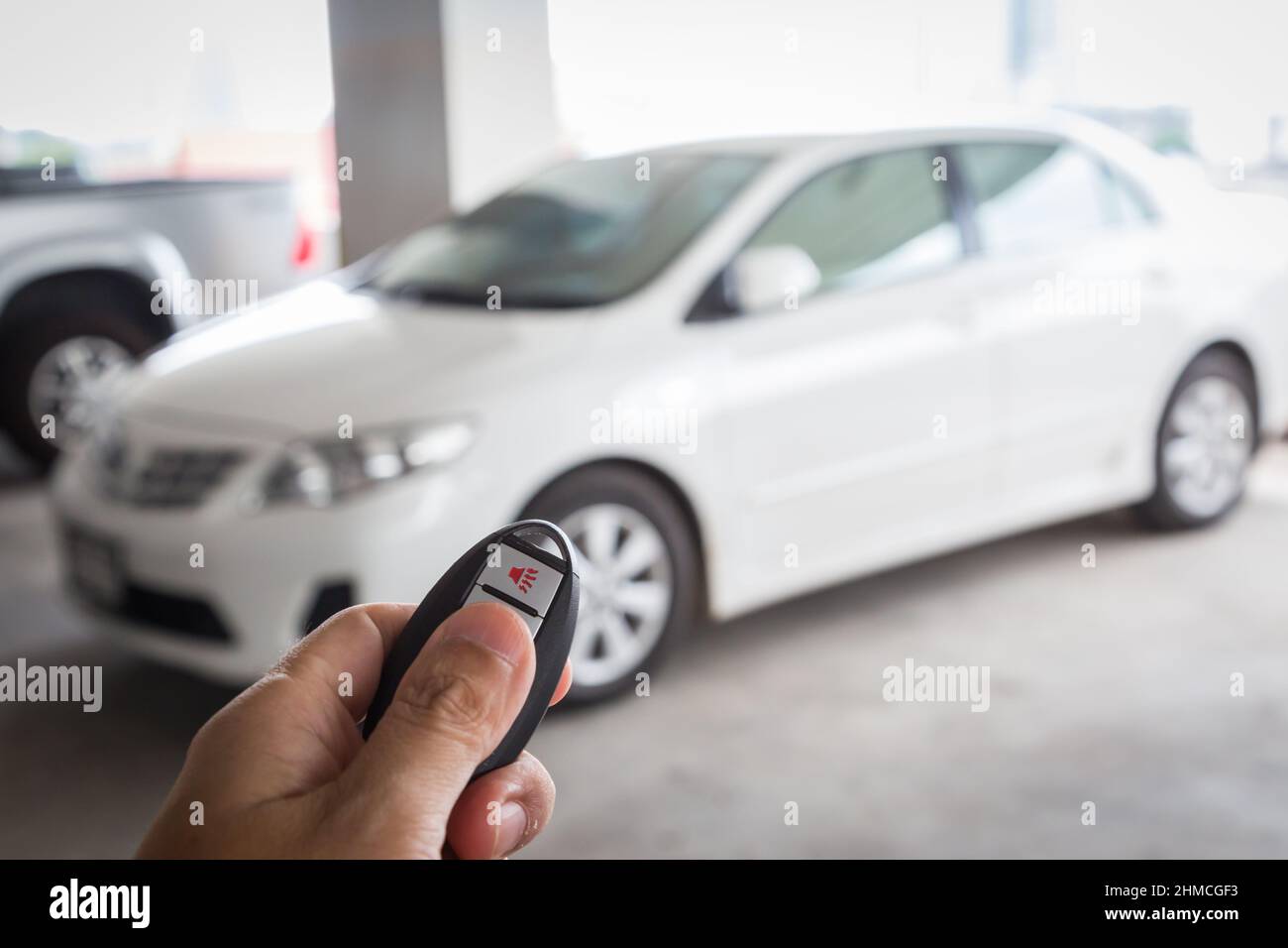 Hand holding button on the remote car at car park background Stock ...