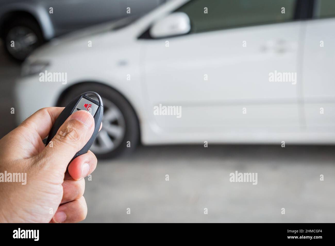 Hand holding button on the remote car at car park background Stock ...