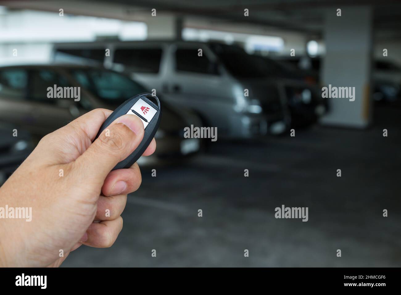 Hand holding button on the remote car at car park background Stock ...