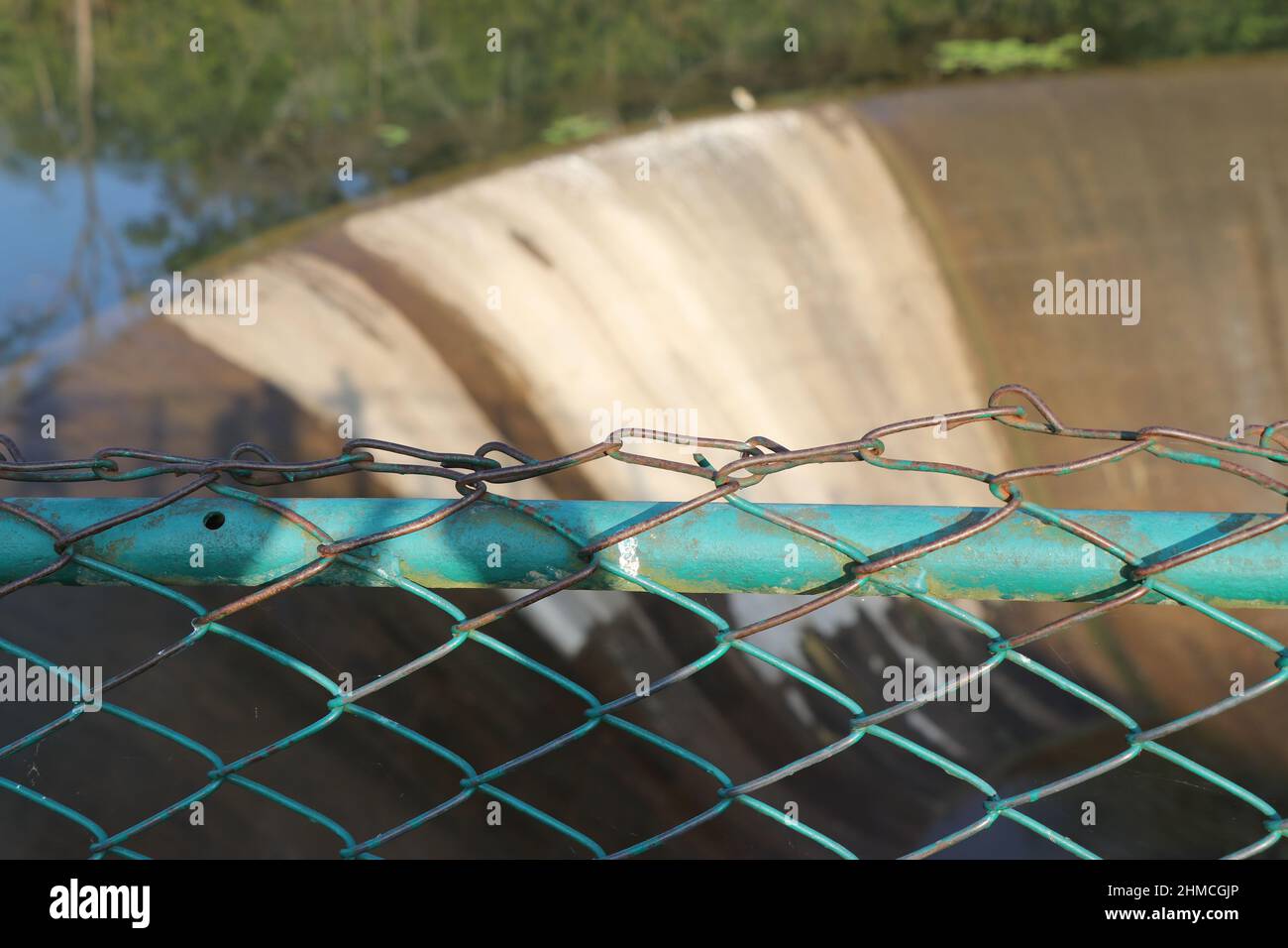 Focus on metal mesh fencing around the local dam, behind which you can ...
