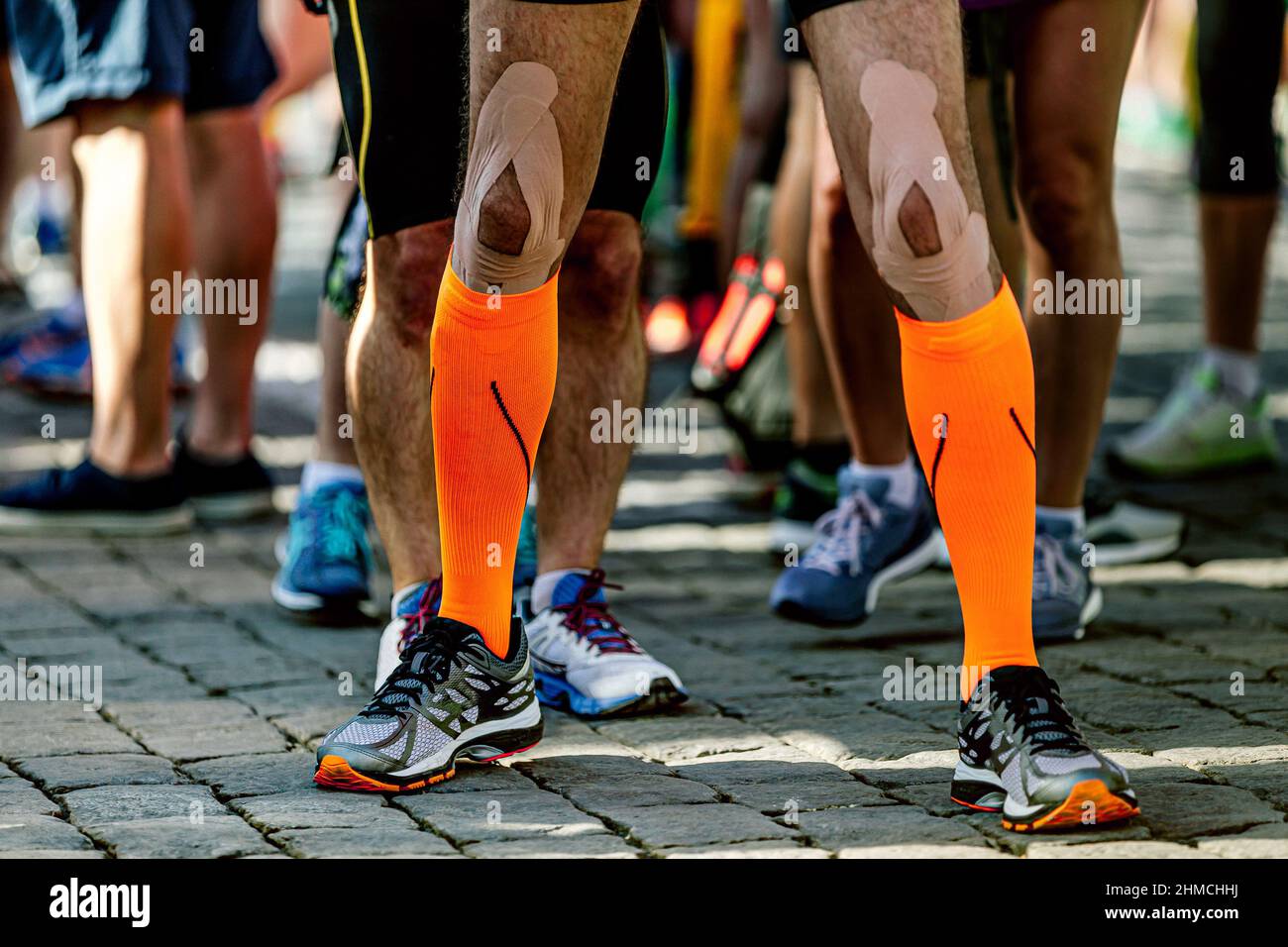 legs male runner in compression socks and kinesio tape on his knees ...