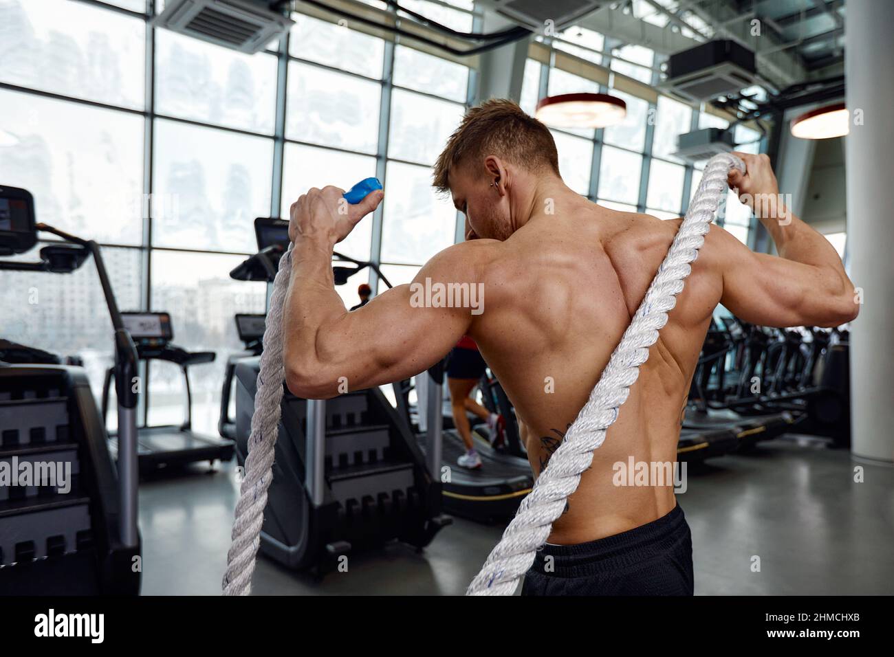 Muscular powerful aggressive man training with rope in functional ...