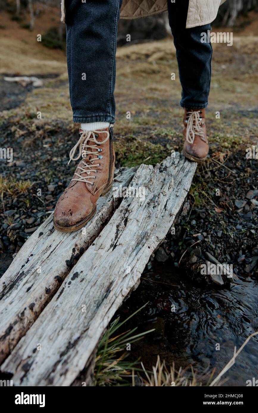 a woman walks across a stream on a plank in boots Stock Photo - Alamy