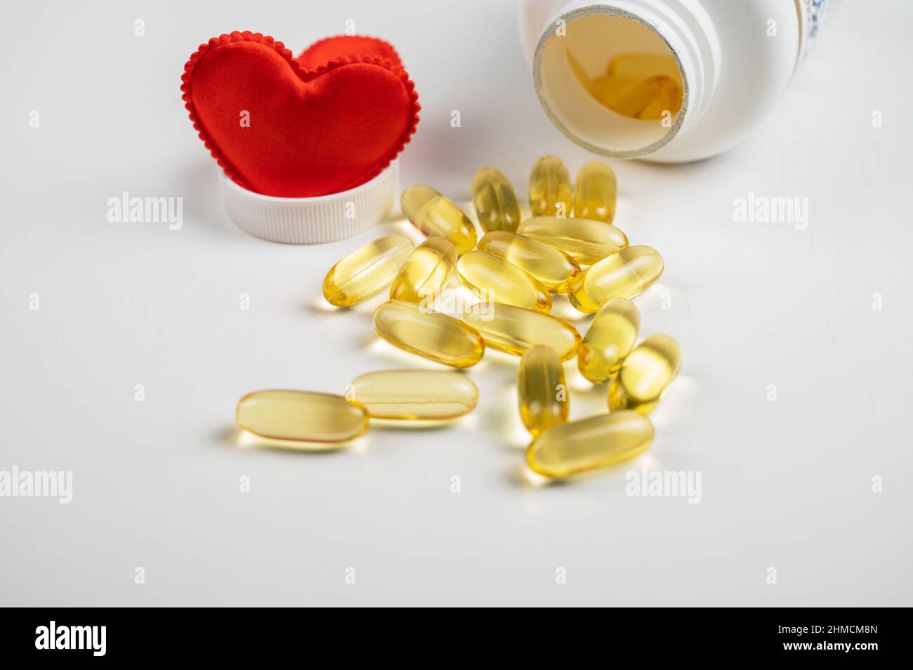 Gold fish oil isolated on white background with red hearts. Pile of ...