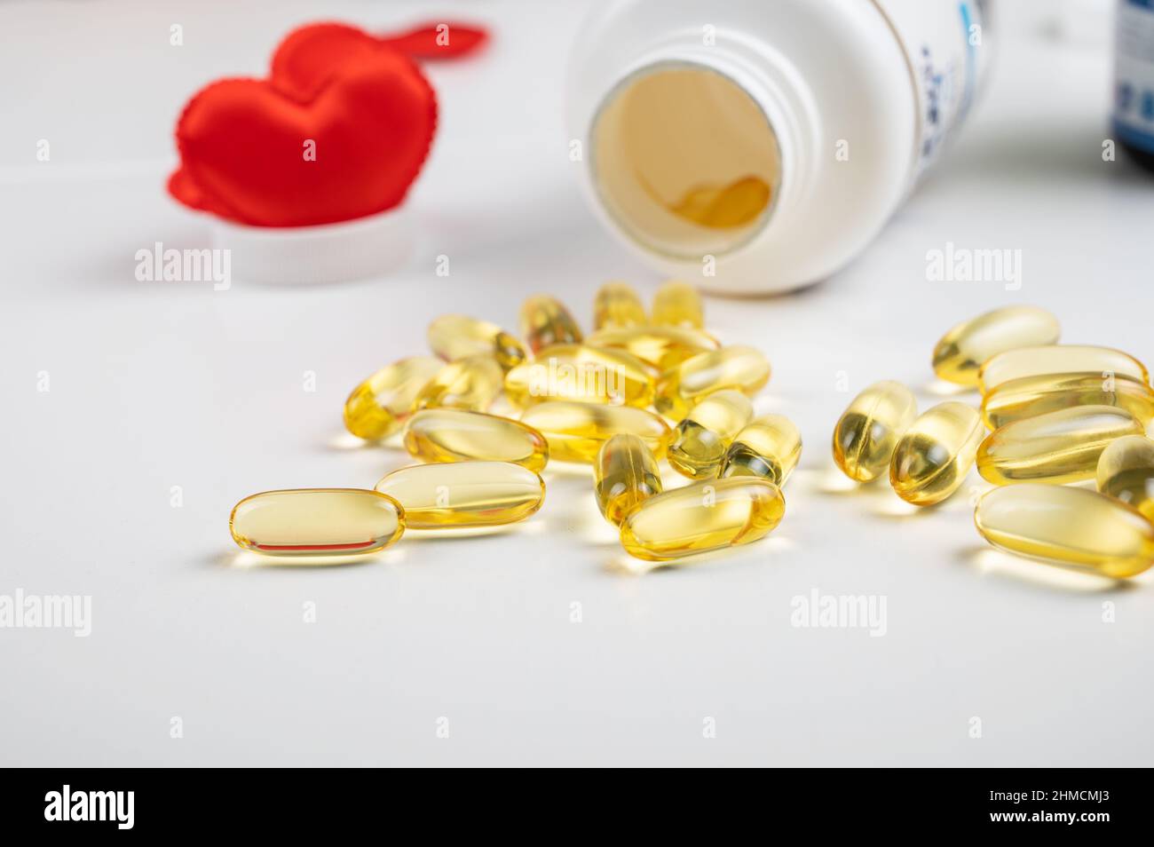 Gold fish oil isolated on white background with red hearts. Pile of ...
