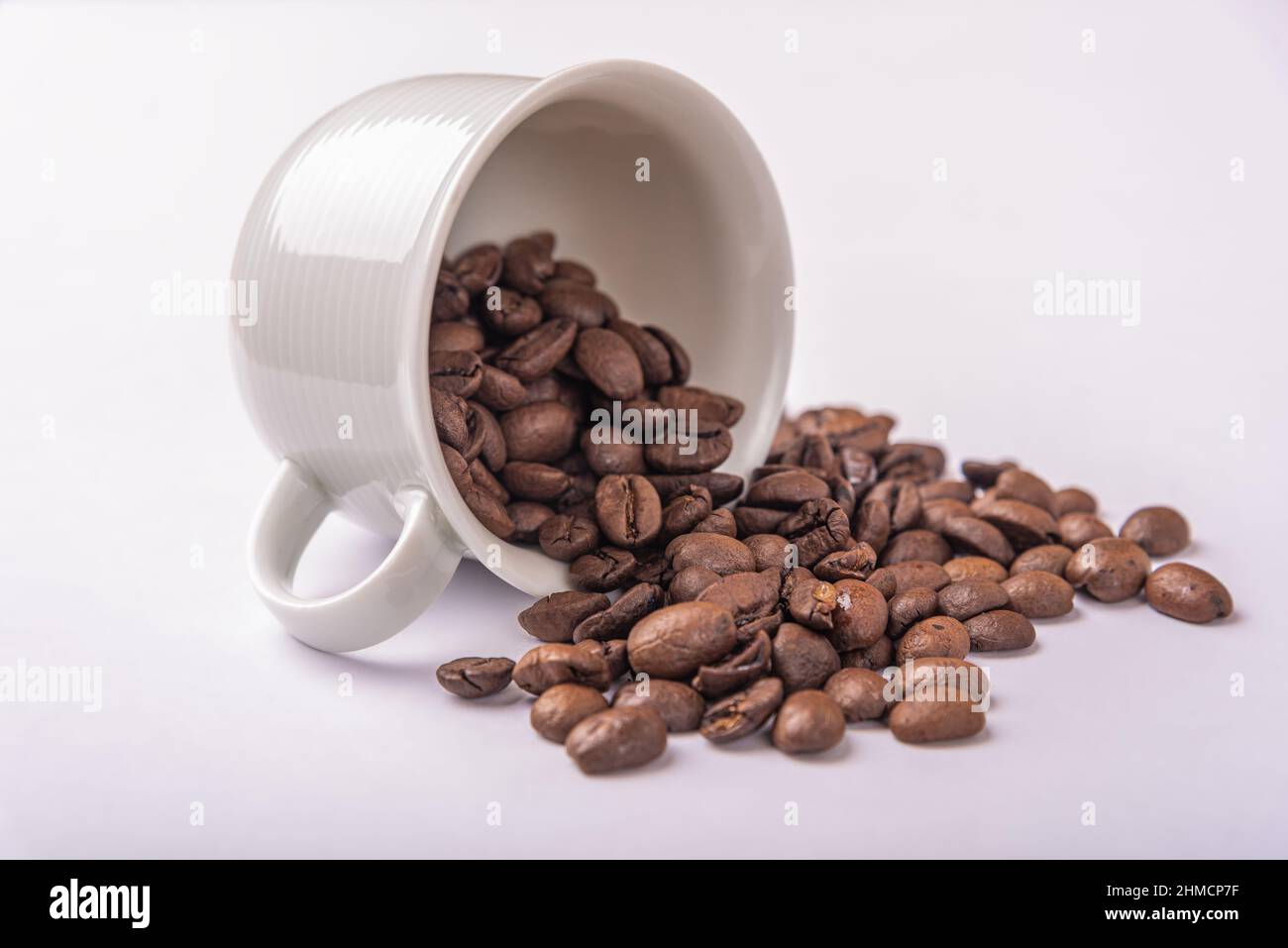 coffee beans spill out of a white ceramic cup Stock Photo - Alamy