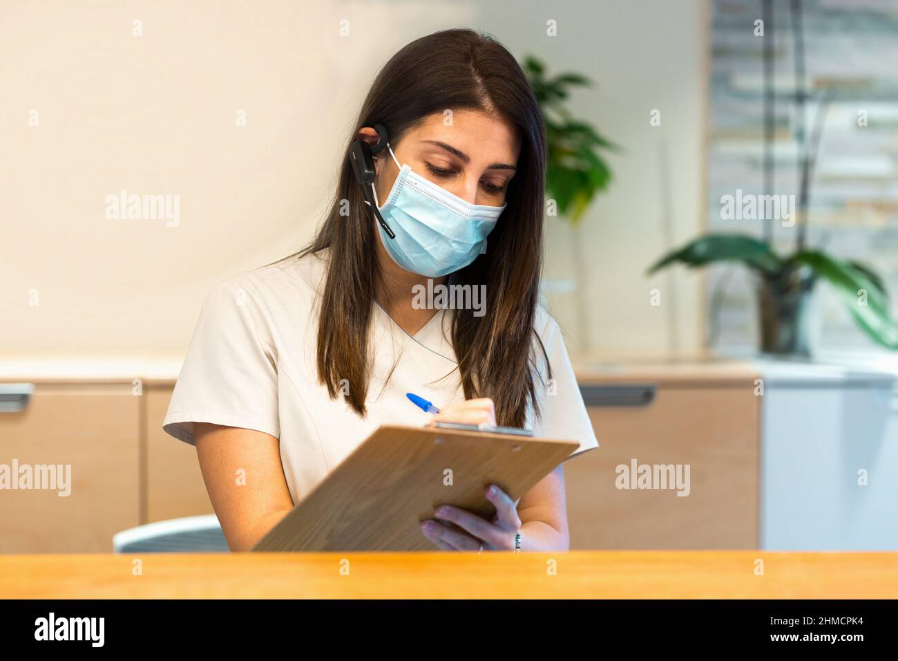 Receptionist taking notes on clipboard at medical center Stock Photo ...