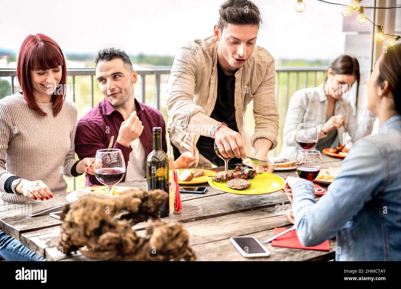 Multicultural friends eating together at roof top party on happy hour ...