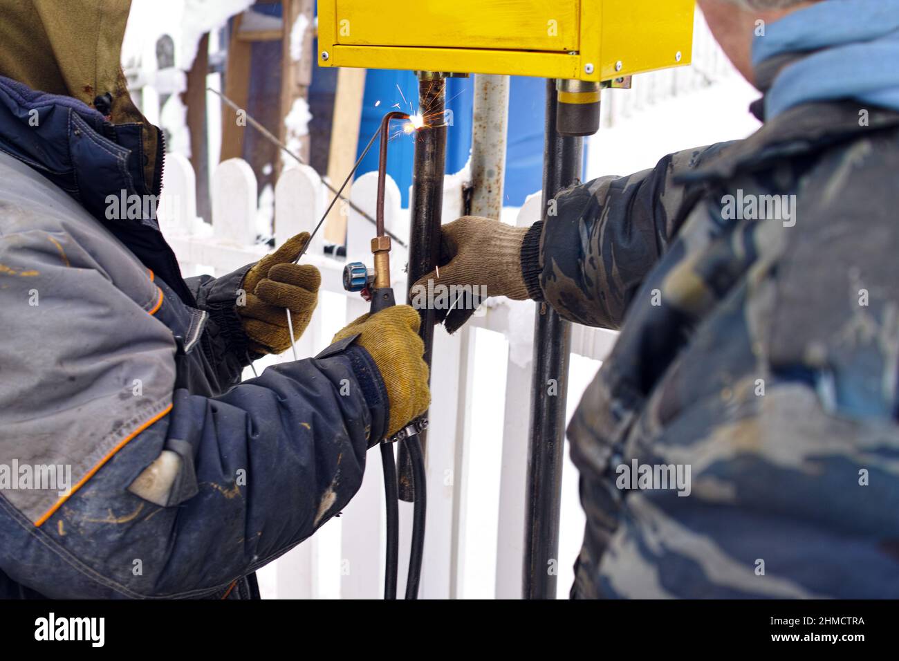 two welders busy with LPG pipeline maintenance, outdoor winter scene ...
