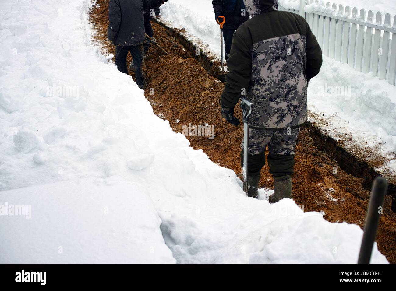 group of workers in dirty clothes digging a trench in winter Stock ...
