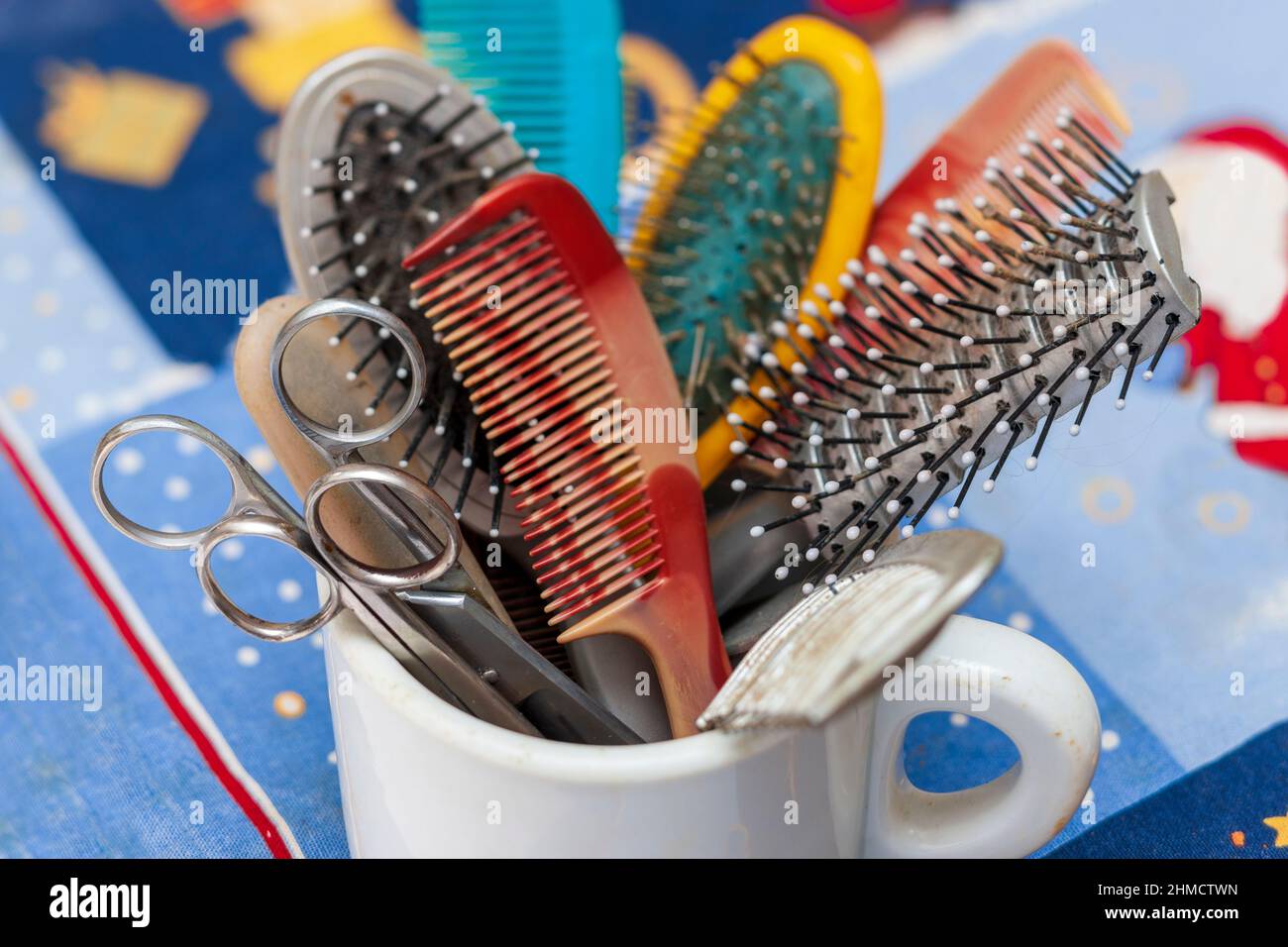 collection of hairbrushes, combs and scissors in a mug, indoor closeuo ...