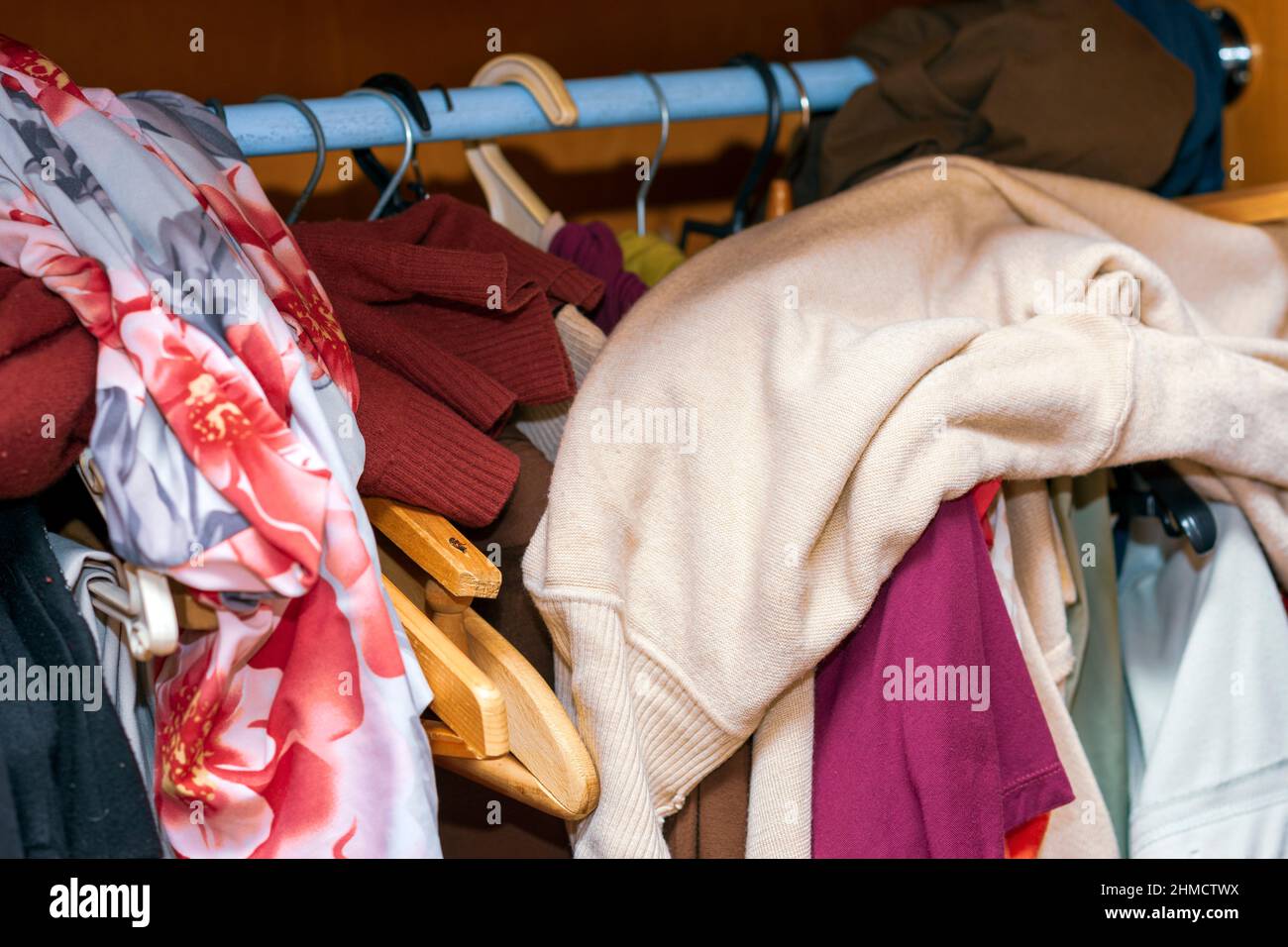 an open wardrobe with collection of clothing in mess, indoor closeup ...