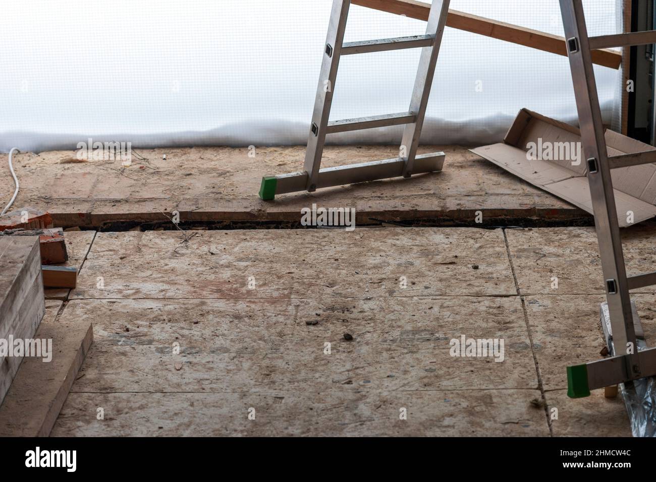 expandable aluminium ladder on the dirty floor of unfinished building ...