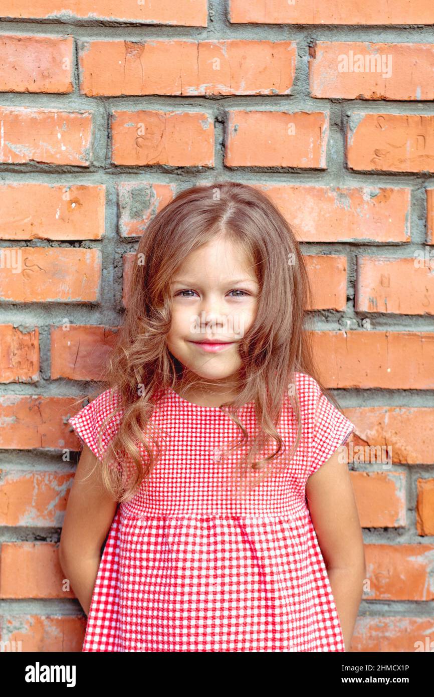 Serious child kid on brick wall as background, waist up looking at ...
