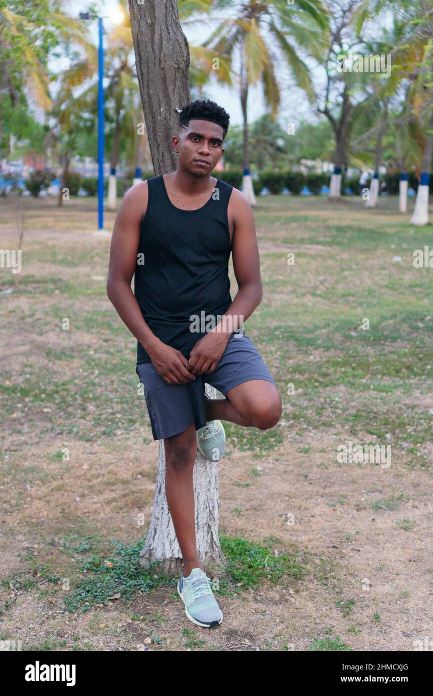 Young man in the park leaning against the tree Stock Photo - Alamy