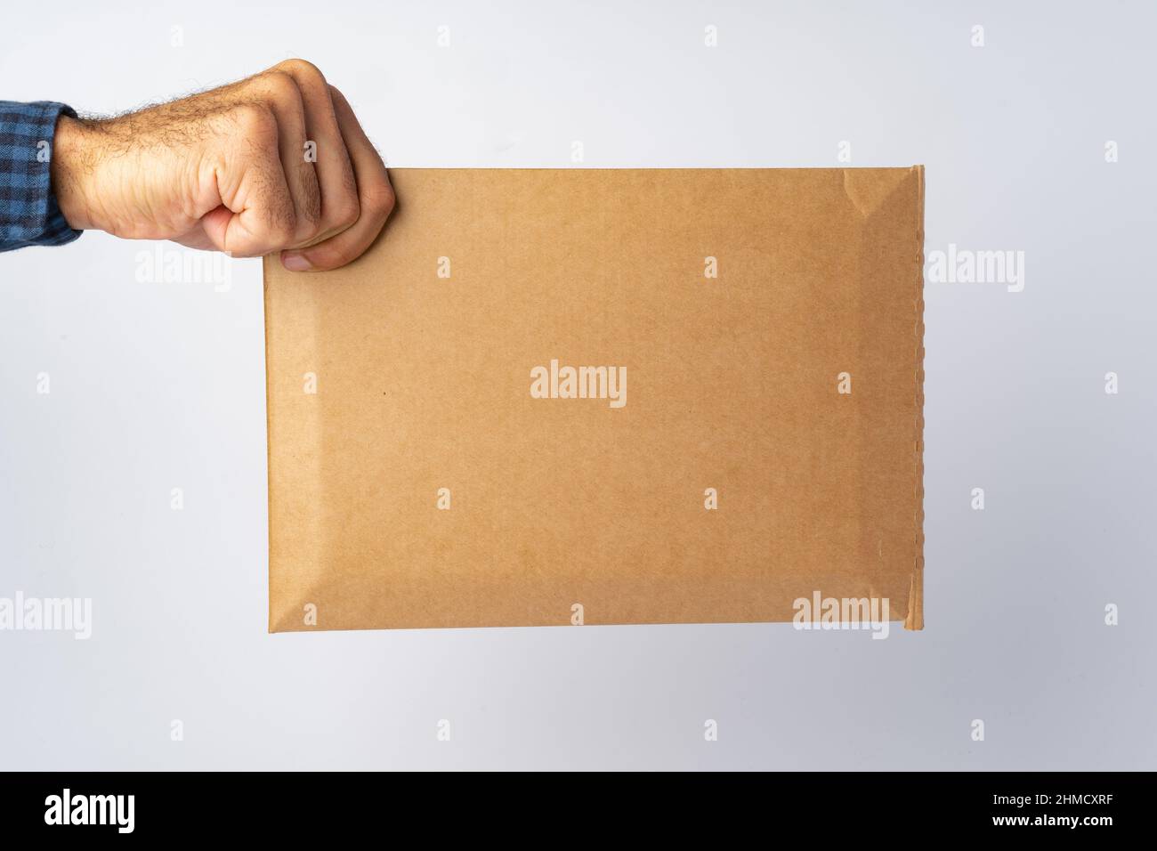 Male hand holding parcel post against white background Stock Photo - Alamy
