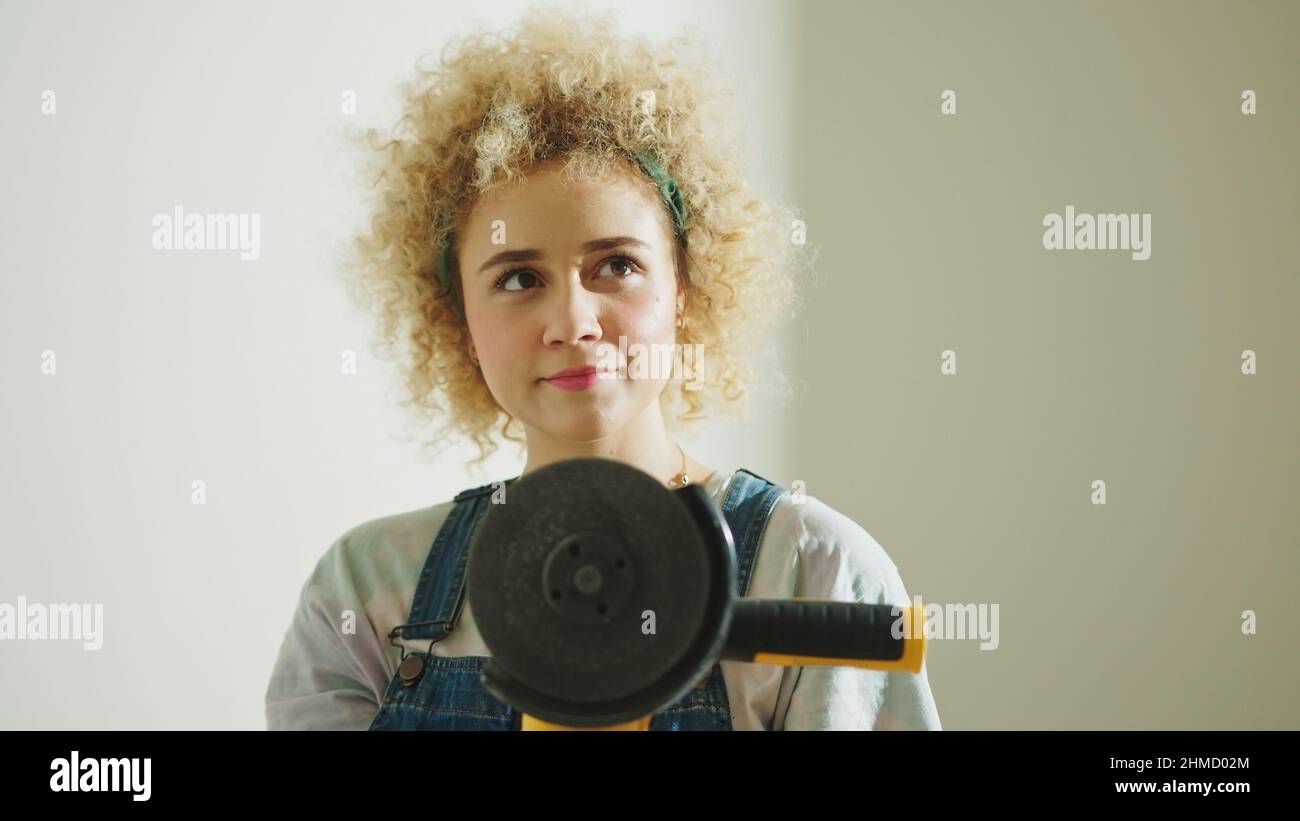 Pensive student girl holding a disc angle grinder - wondering crafty ...