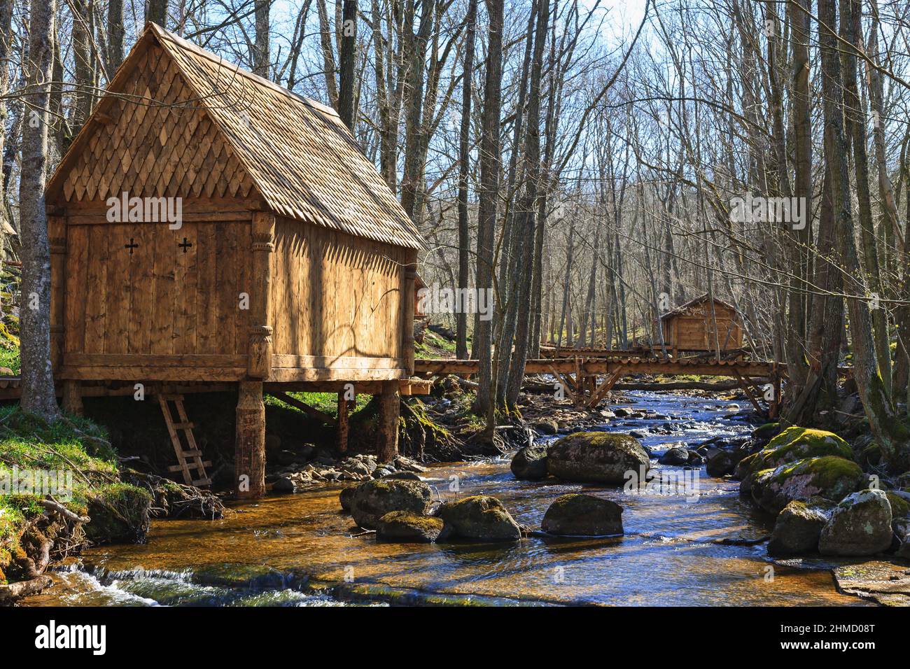 Beautiful log cabins by a stream in the forest and footbridge over the ...