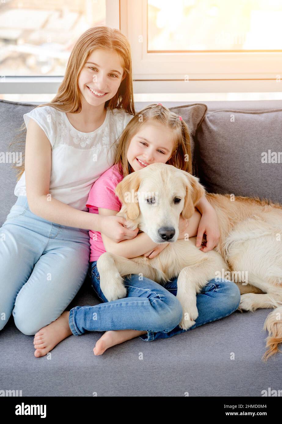 Happy sisters cuddling cute dog Stock Photo - Alamy