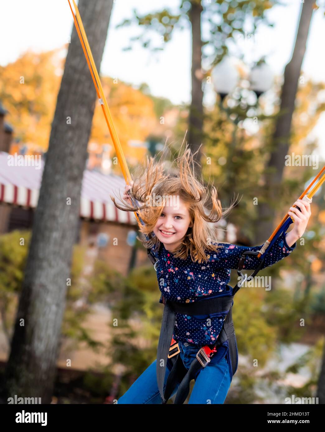 Smiling little girl jumping on trampoline rope Stock Photo - Alamy
