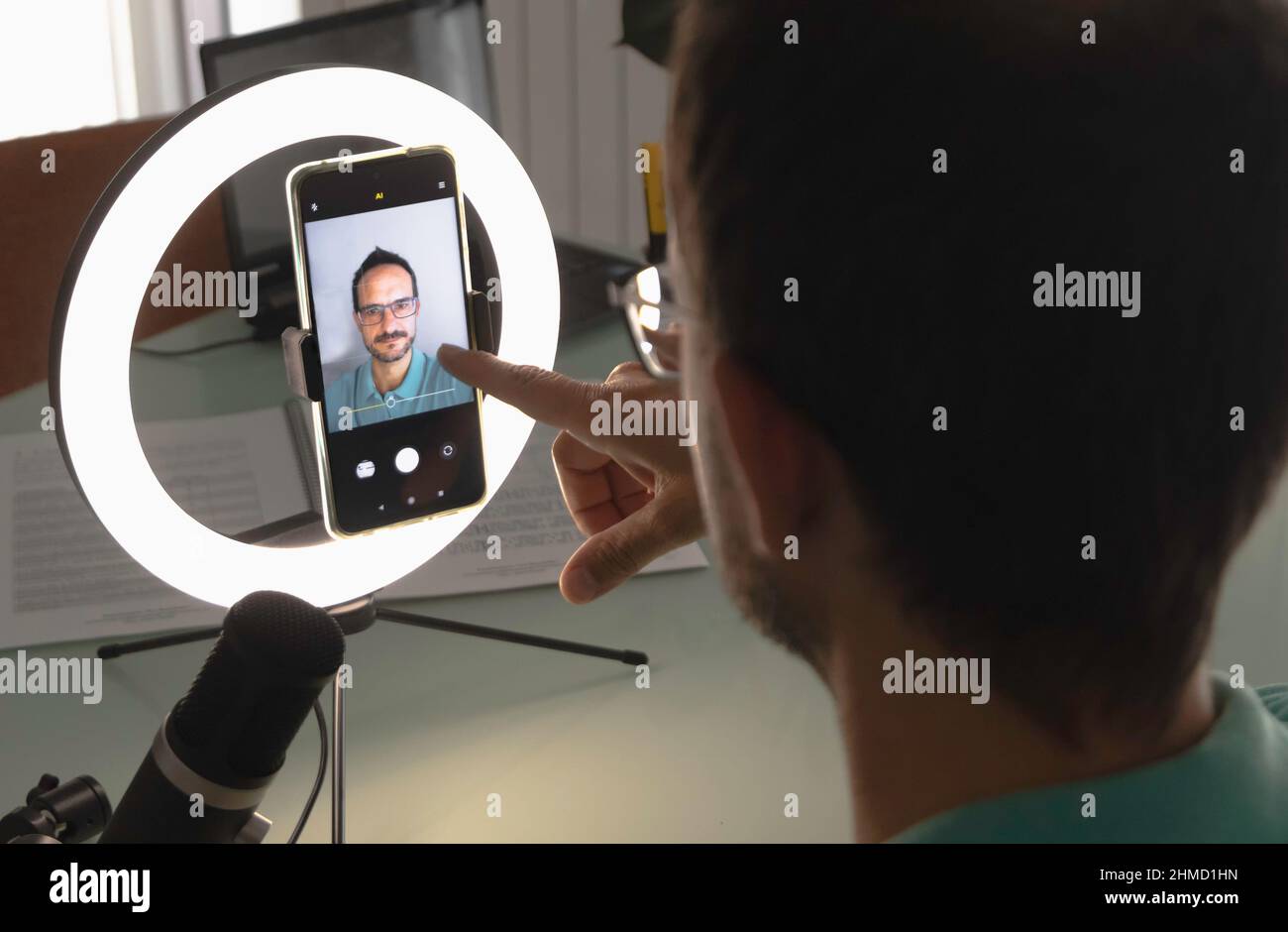 one man setting up a video call with his smart phone and a light ring ...