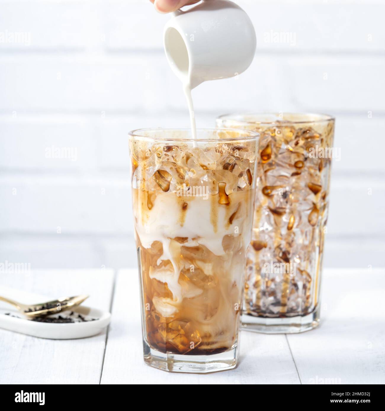 Making bubble tea, pouring milk into brown sugar pattern drinking glass ...