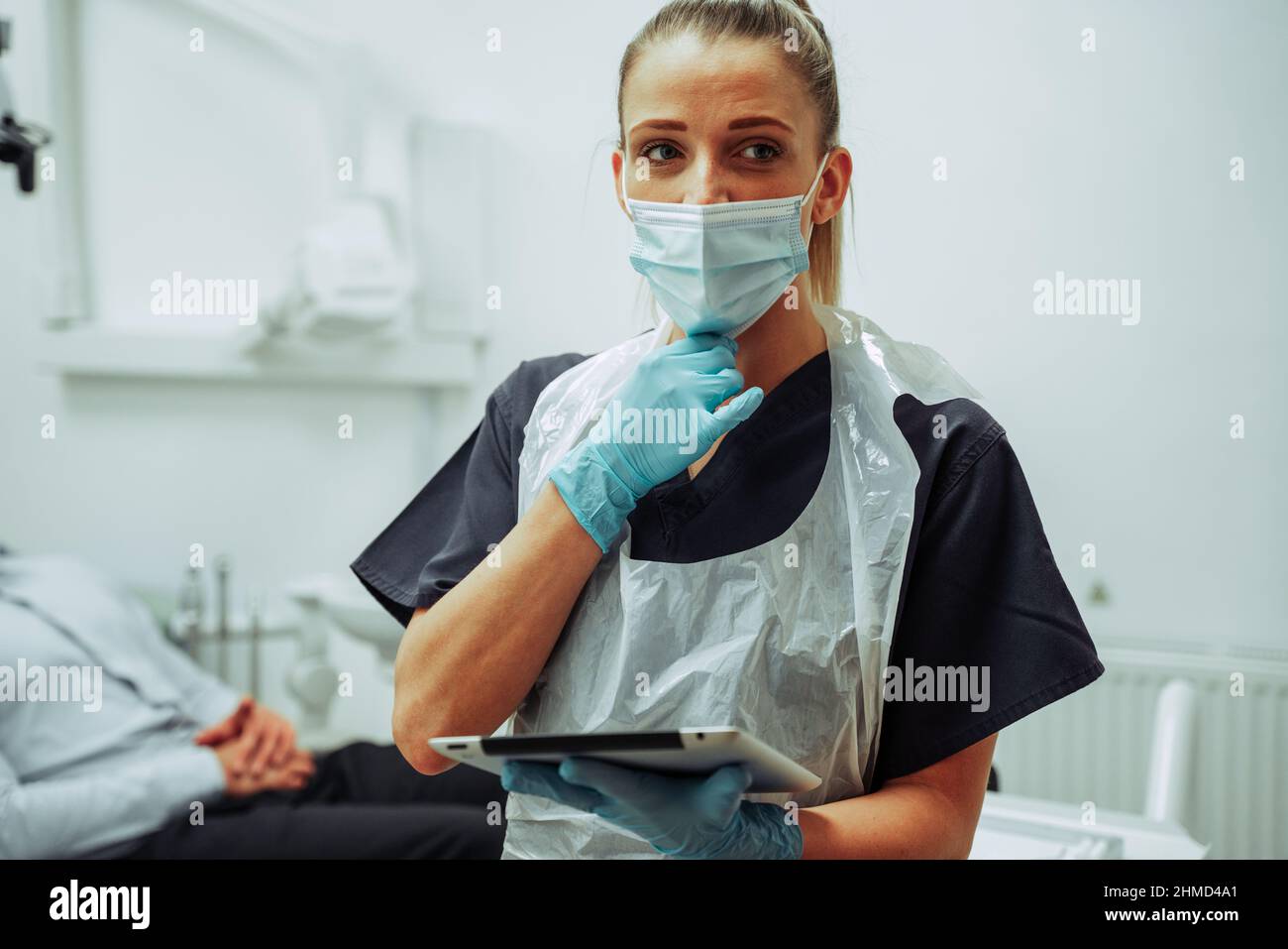 Caucasian female nurse wearing surgical mask and holding digital tablet ...