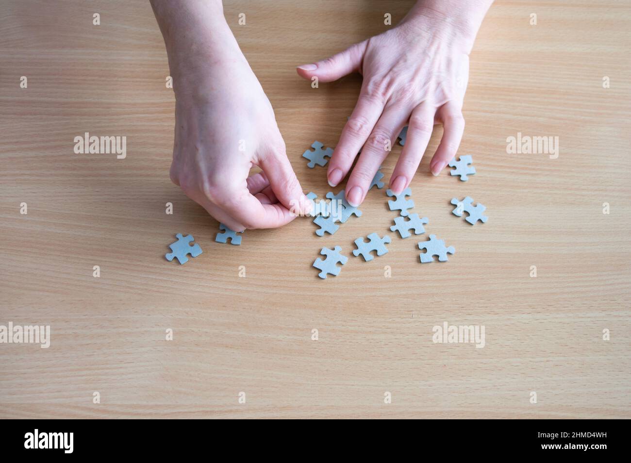 Hands arranging puzzle pieces on table Stock Photo - Alamy