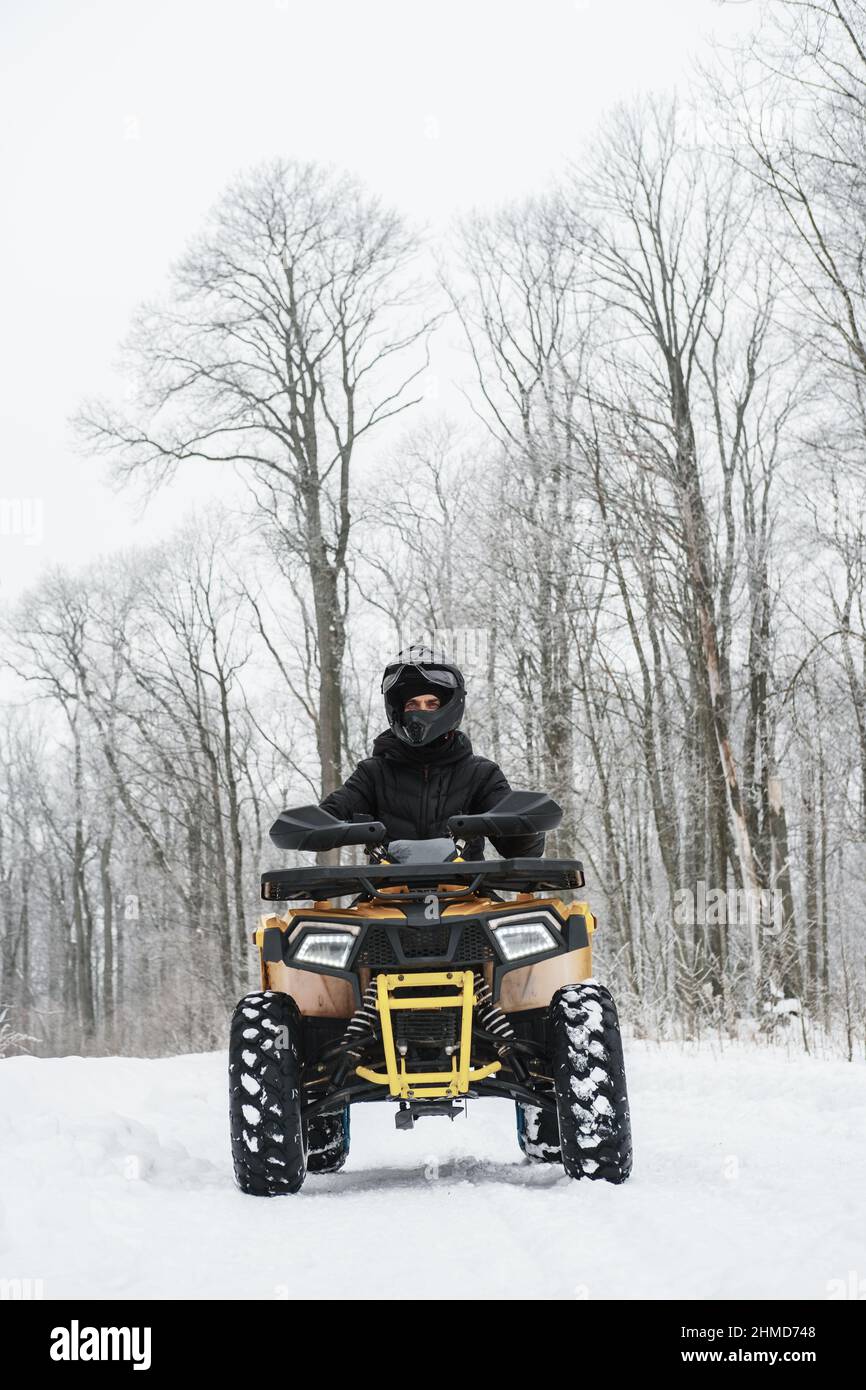 Hero shot of a man on a quad bike in winter background. Portrait of a ...