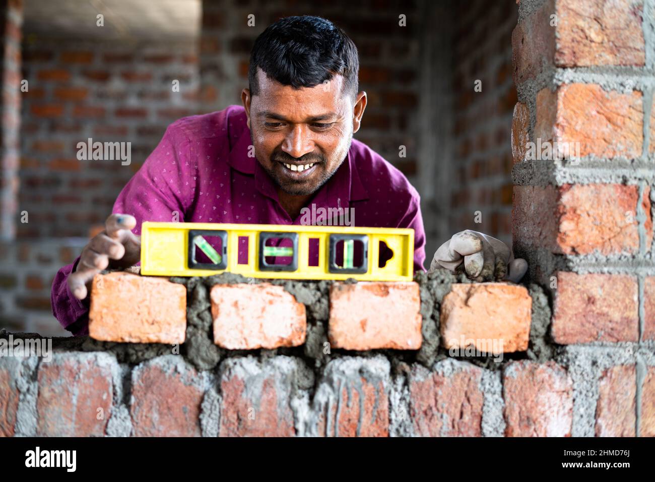 Mason measuring horizontal surface of wall using spirit level at ...