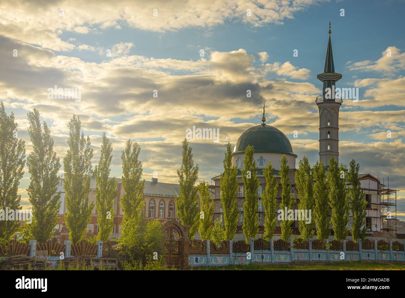 Summer landscape with mosque, minaret and pyramidal poplars in rays ...