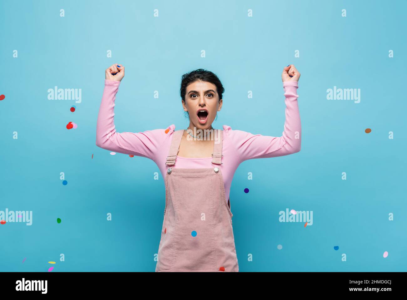 overjoyed woman screaming and showing win gesture under falling ...