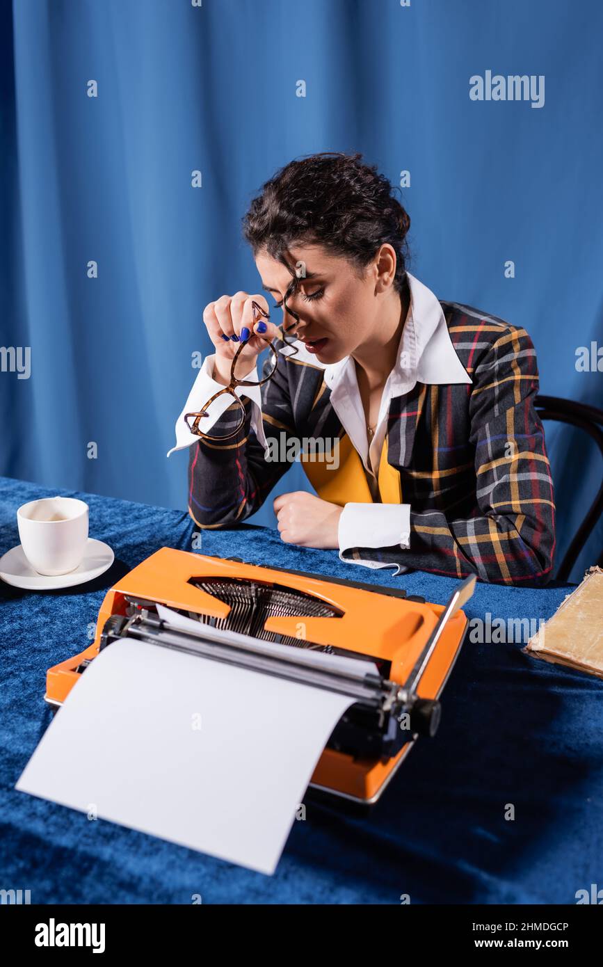 tired journalist sitting with closed eyes near coffee cup and vintage ...