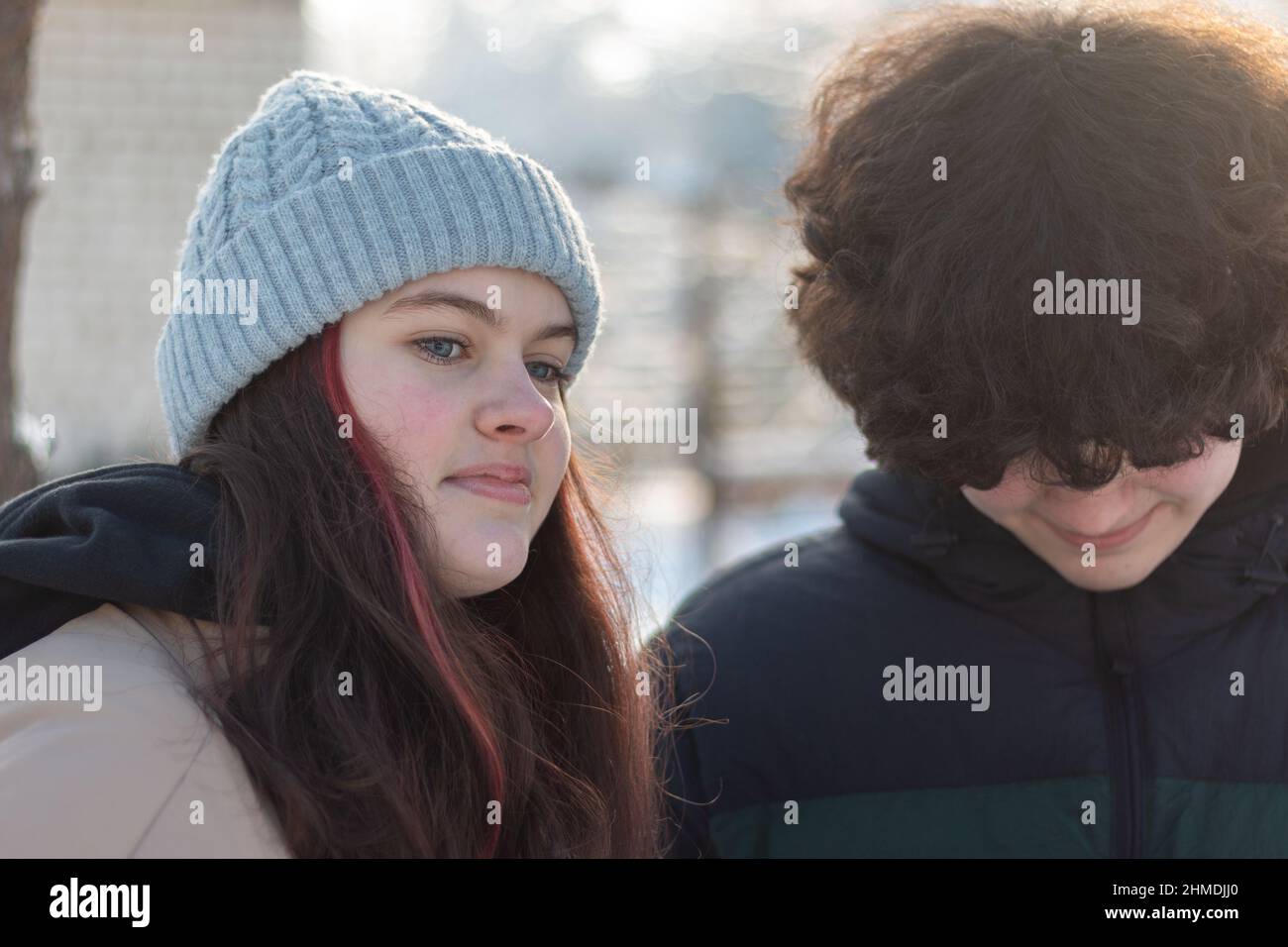 Teenagers in winter clothes look at the smartphone screen while viewing ...