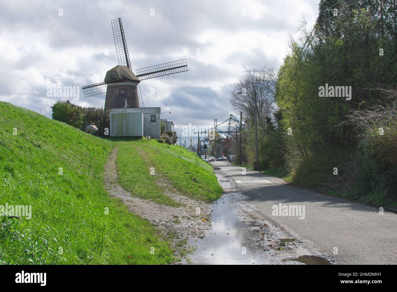 Swampy path with a windmill on the hill and industry in the background ...