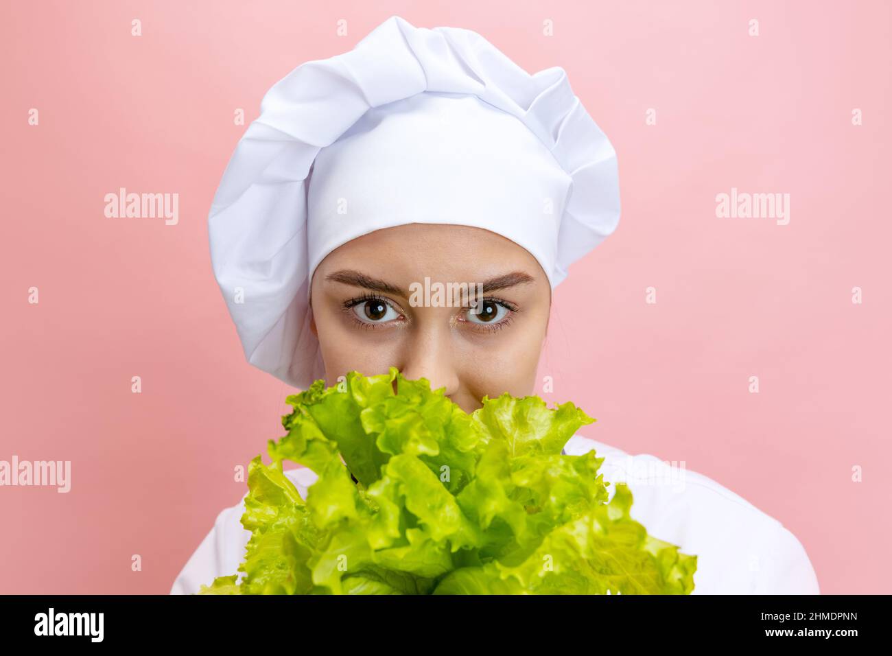 Young woman, lady-cook, chef in white uniform posing isolated on pink ...