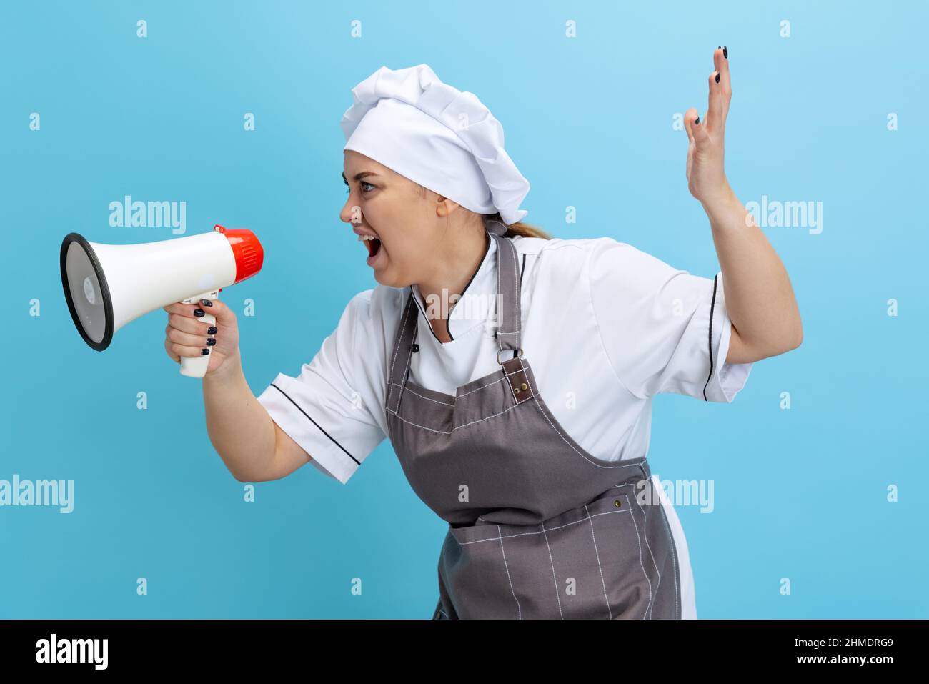 Portrait of young woman, lady-cook, chef in white uniform shouting at ...