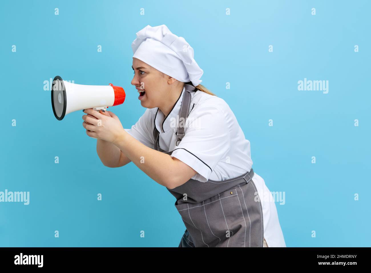 Portrait of young woman, lady-cook, chef in white uniform shouting at ...