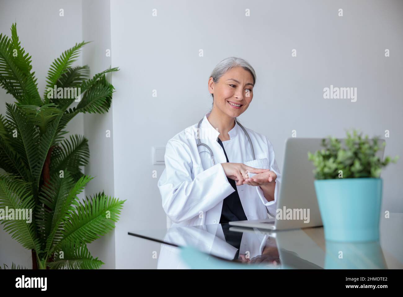 Asian female physician communicating in sign language with patient by ...