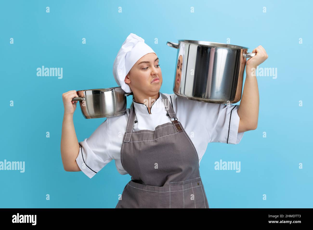 Portrait of young annoyed woman, lady-cook, chef in white uniform with ...