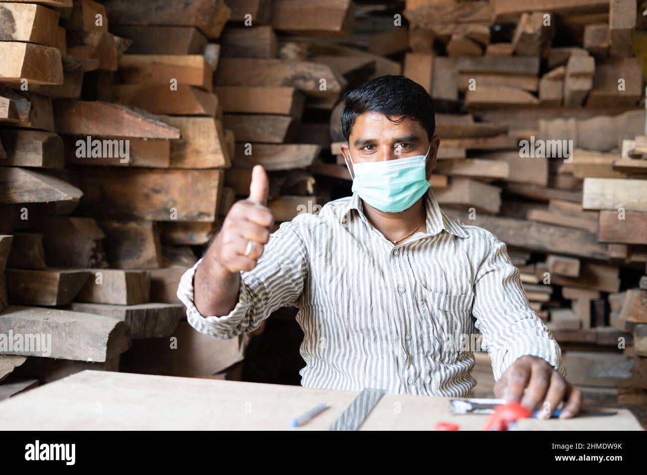 Indian carpenter with medical face mask showing thumbs up by looking ...